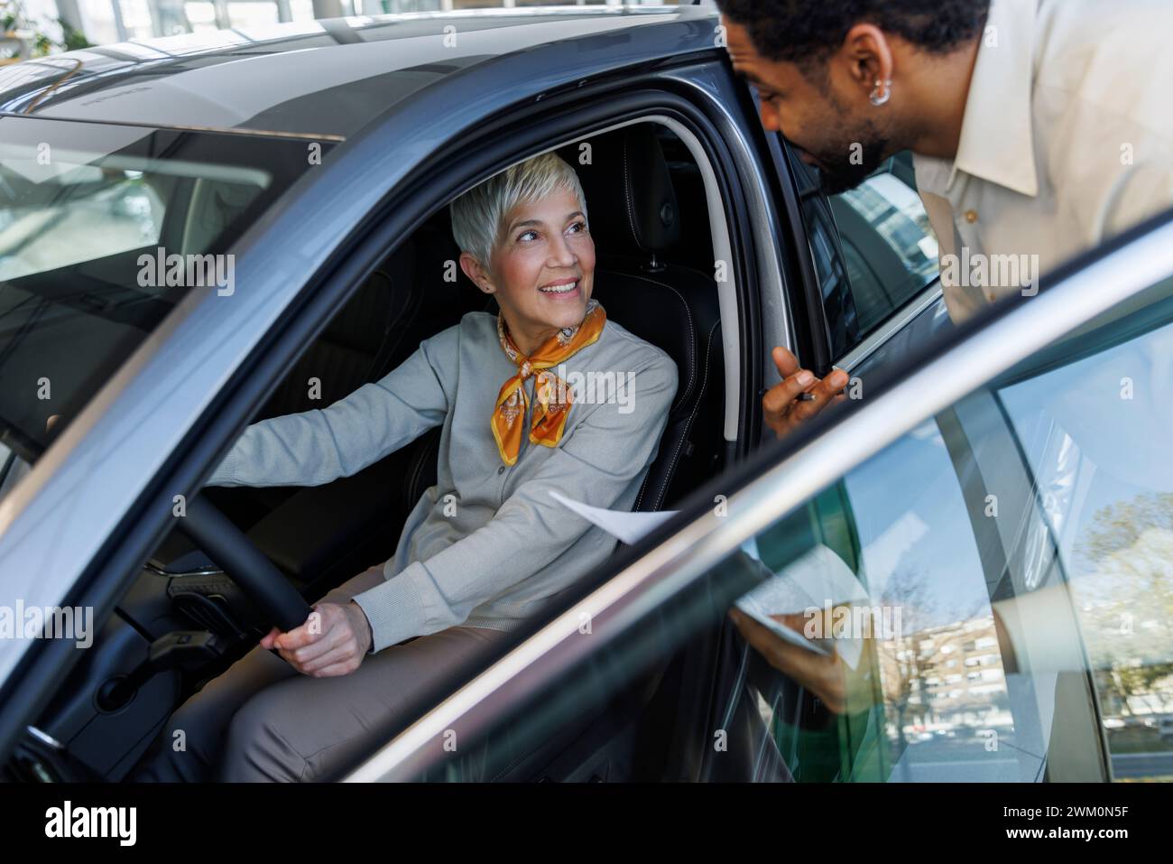 Salesperson discussing with smiling customer sitting in car Stock Photo ...