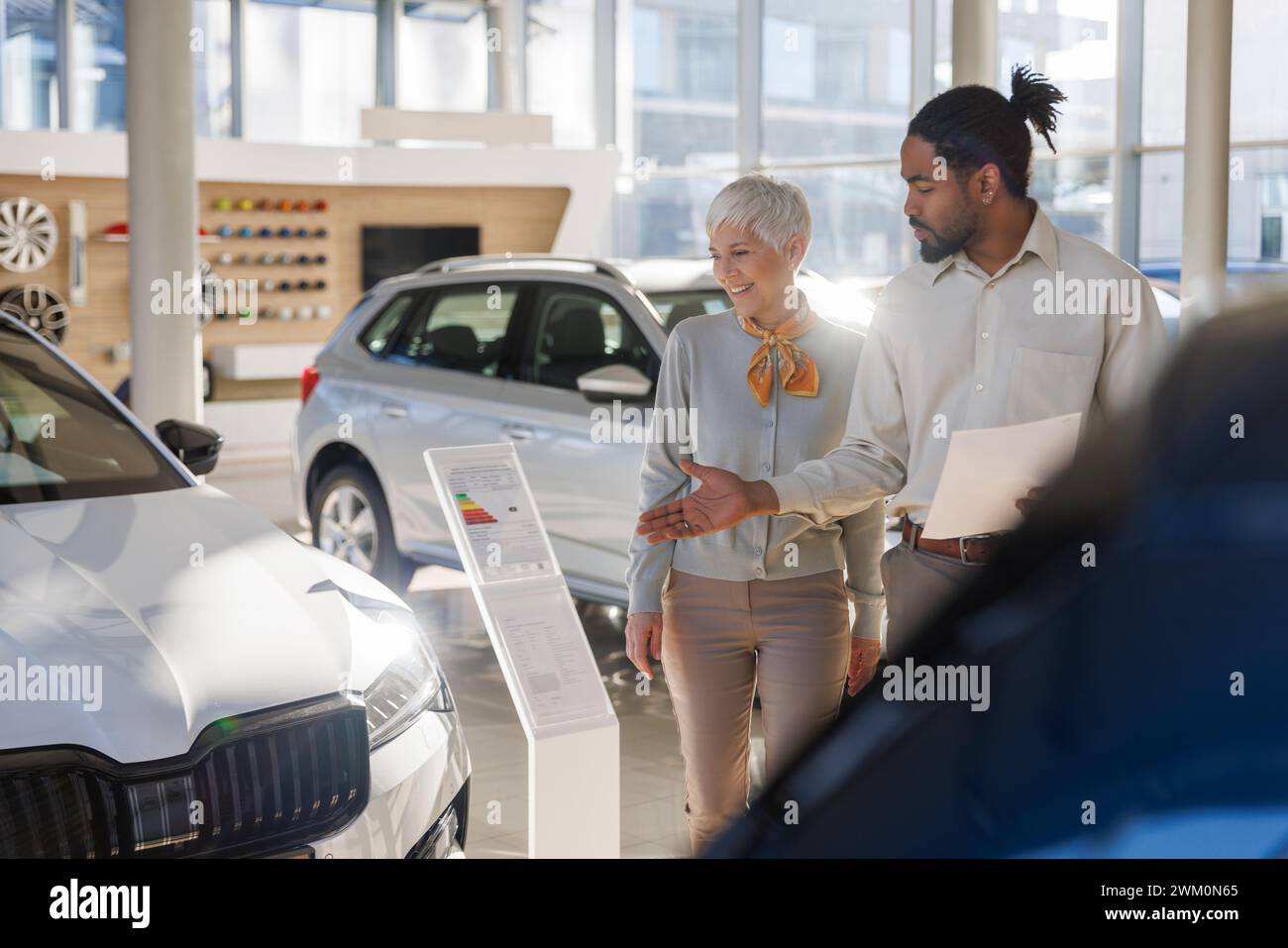 Salesperson having discussion over car with smiling customer at ...