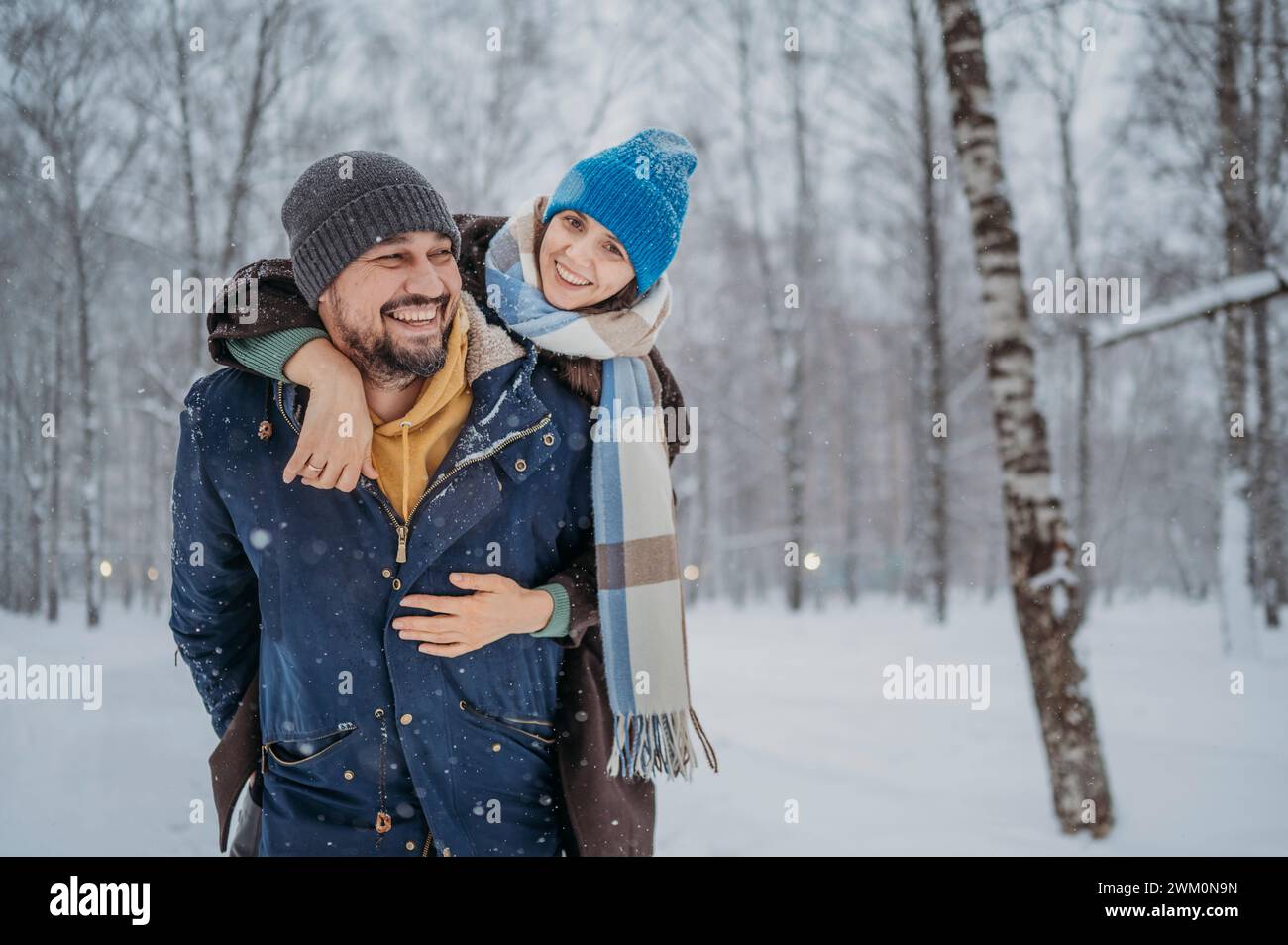 Happy man giving piggyback to woman at park in winter Stock Photo - Alamy