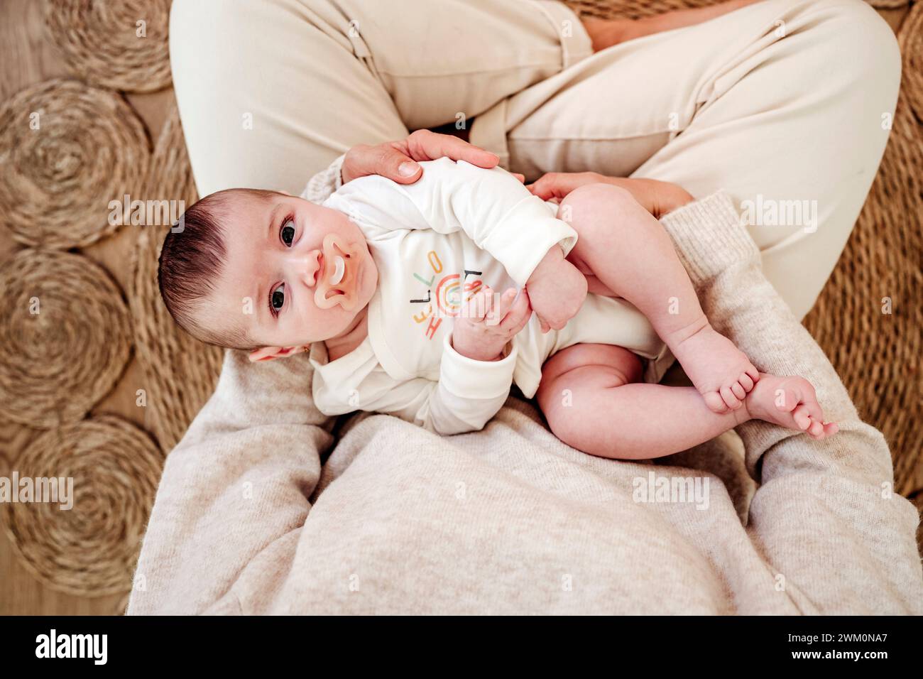 Baby girl sucking pacifier in mother's arms at home Stock Photo - Alamy