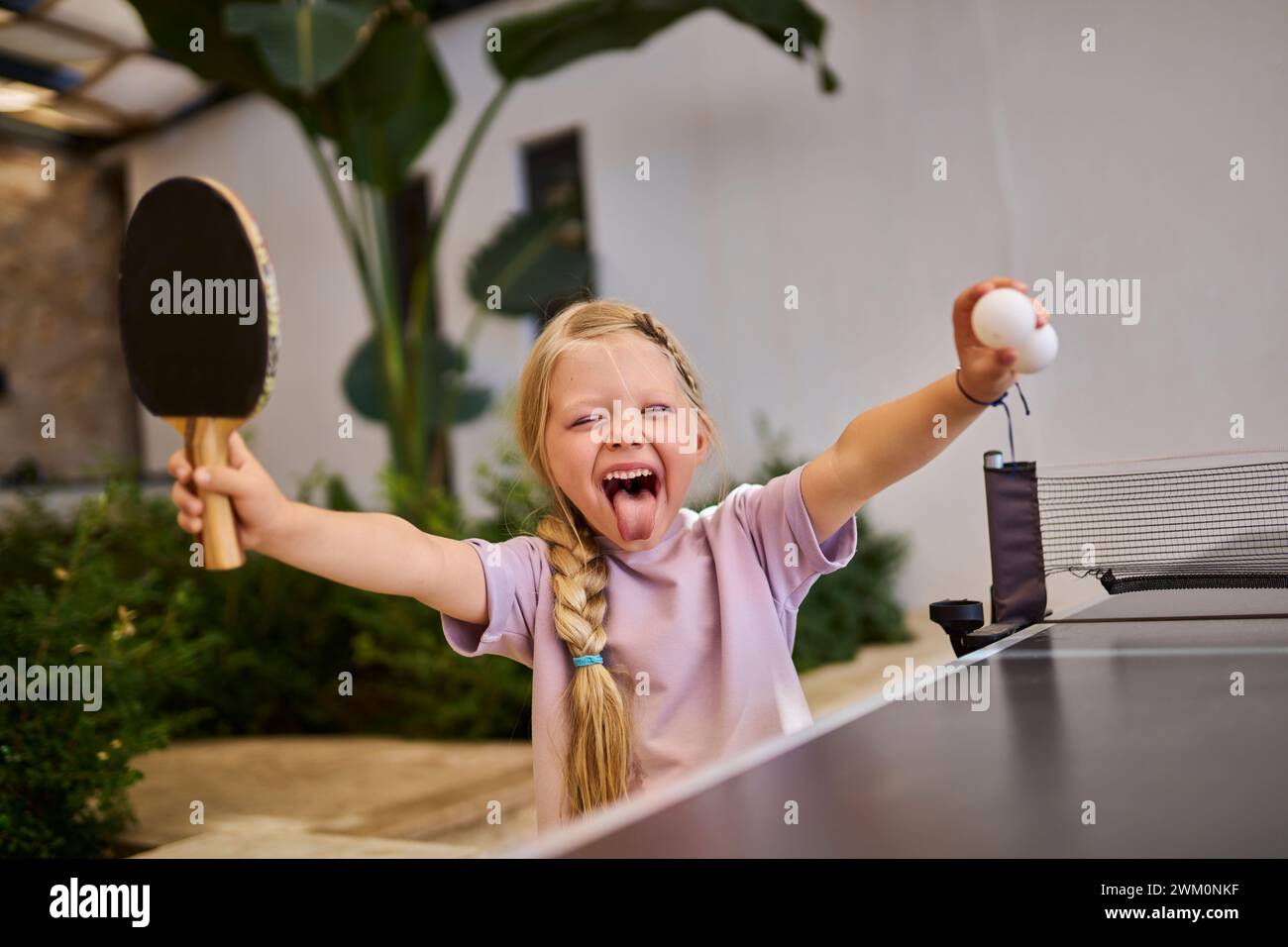 Carefree girl holding table tennis racket and ball at villa Stock Photo ...