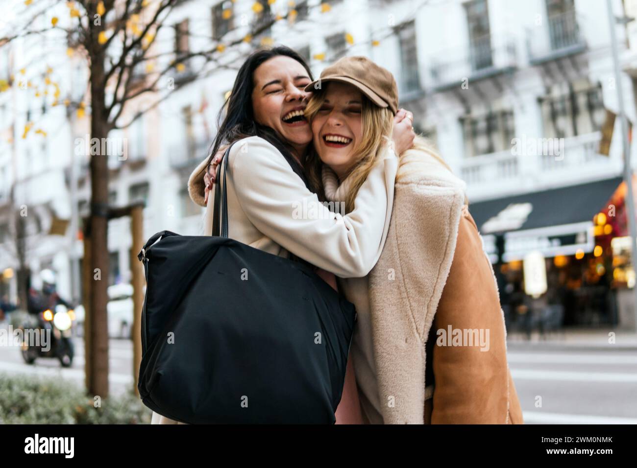 Happy woman laughing with friend standing at street in city Stock Photo ...