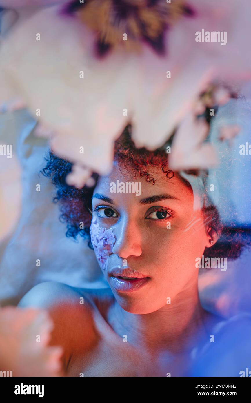 Young woman lying behind glass surface under neon lights Stock Photo ...