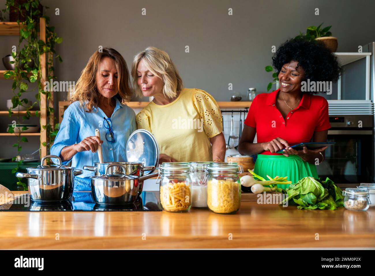 Woman stirring spoon in cooking pan by friends in kitchen at home Stock ...