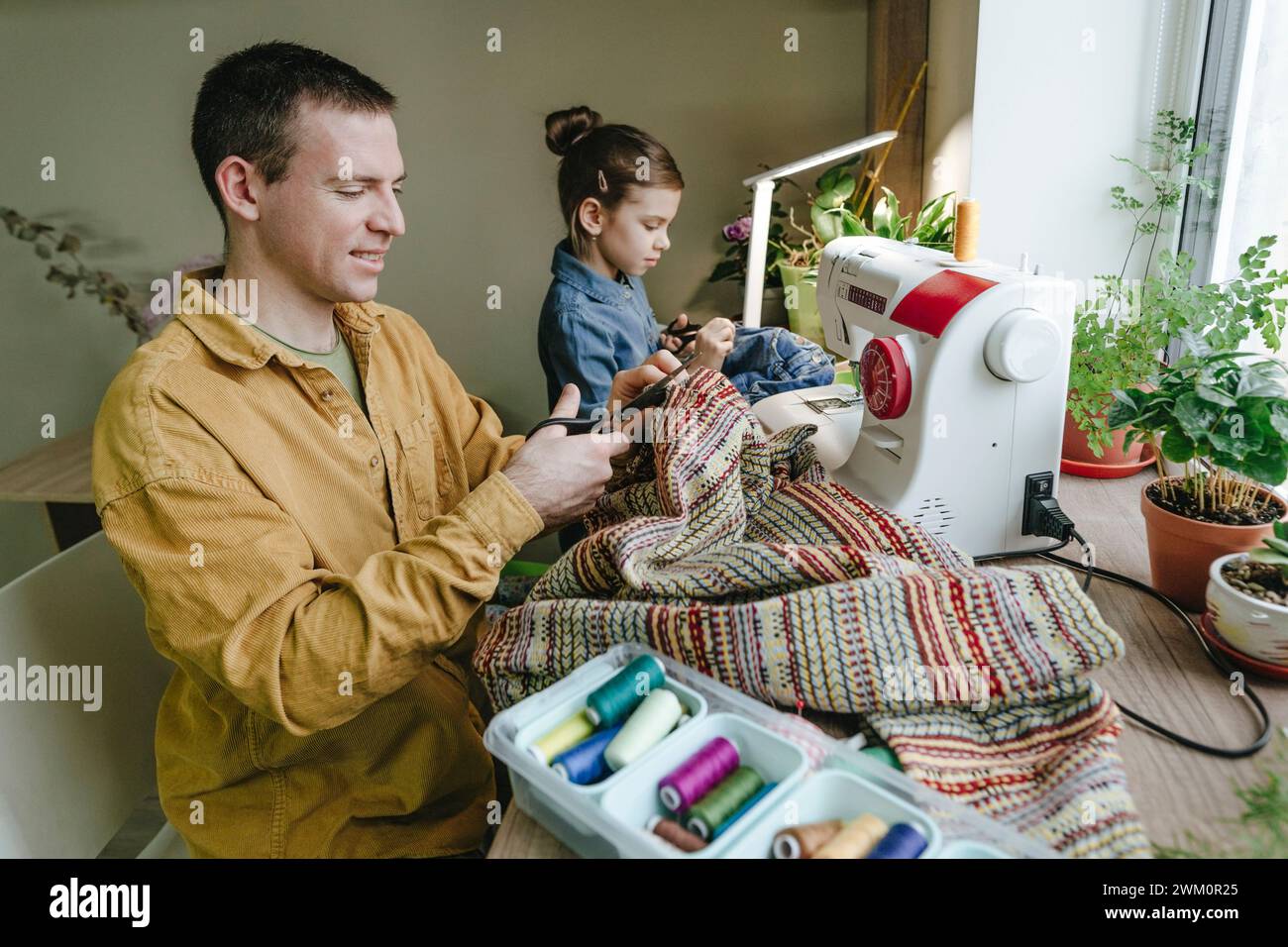 Man cutting fabric with daughter using scissors at home Stock Photo - Alamy