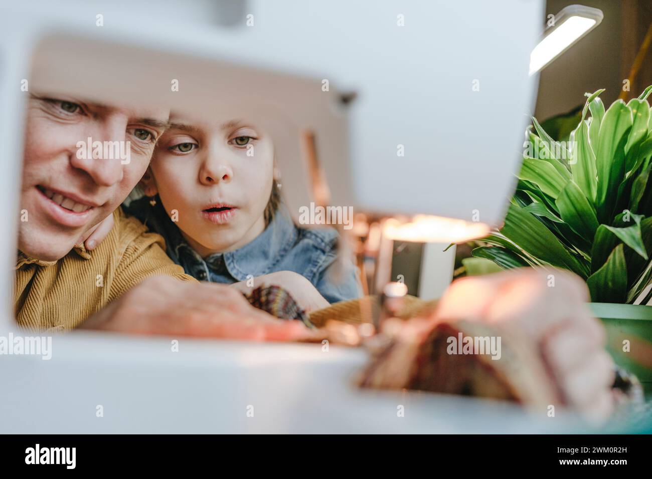 Daughter with father sewing recycled clothes through machine Stock ...