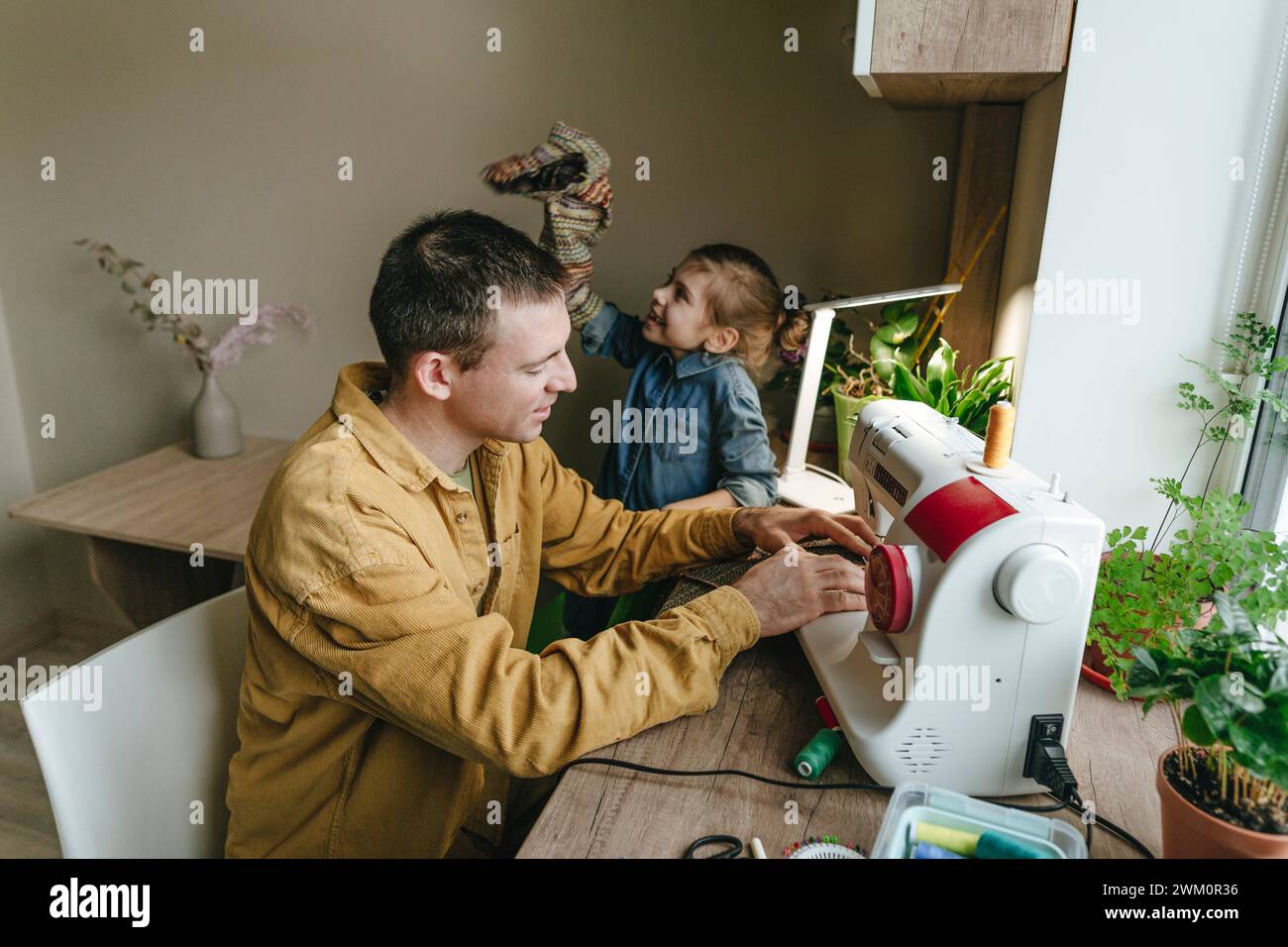 Father sewing recycled clothes through machine at home Stock Photo - Alamy