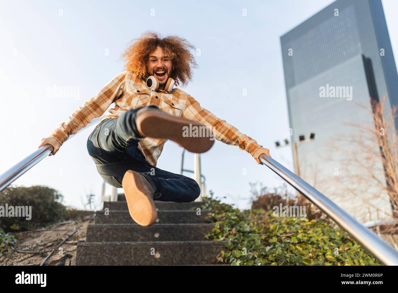 Happy man holding railing and jumping on staircase Stock Photo - Alamy