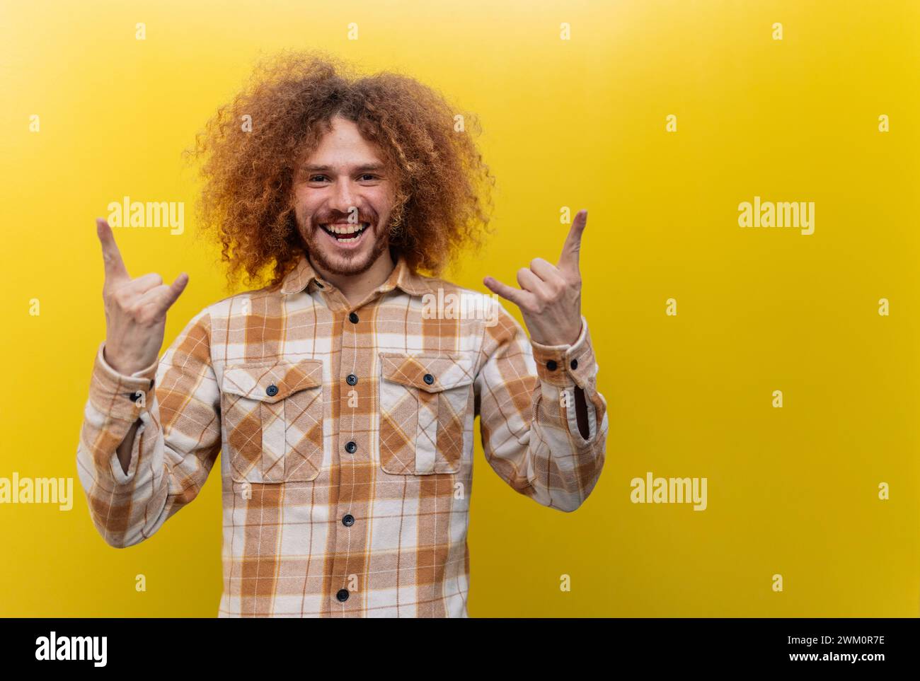 Happy man showing Shaka sign in front of yellow wall Stock Photo - Alamy