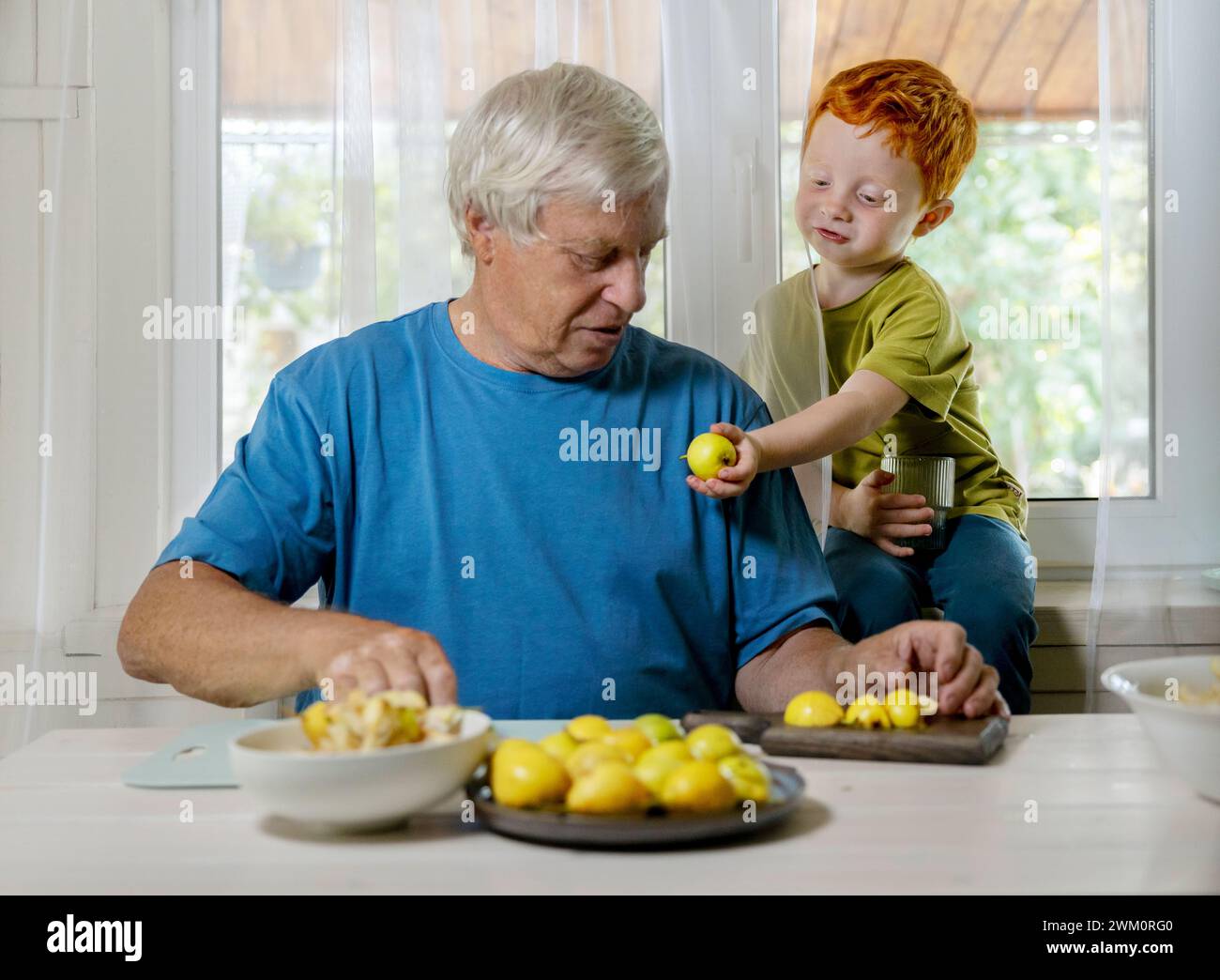 Boy passing fruit to grandfather at home Stock Photo - Alamy