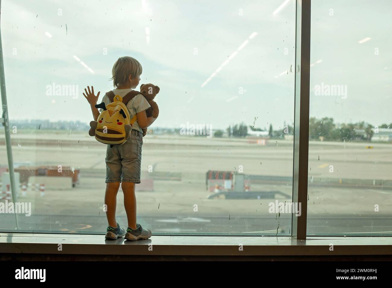 Child, watching from the window of the airport the planes, taking off ...