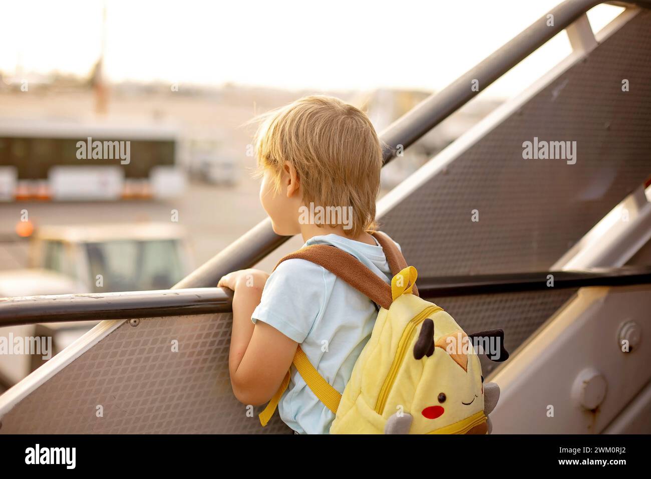 Cute blond child, kid with backpack, boarding airplane at the airport ...