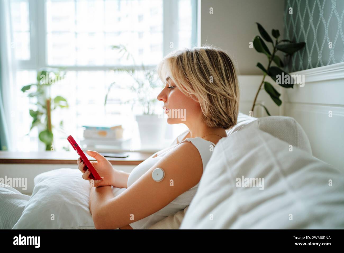 Woman using smart phone with glucose sensor on arm at home Stock Photo ...