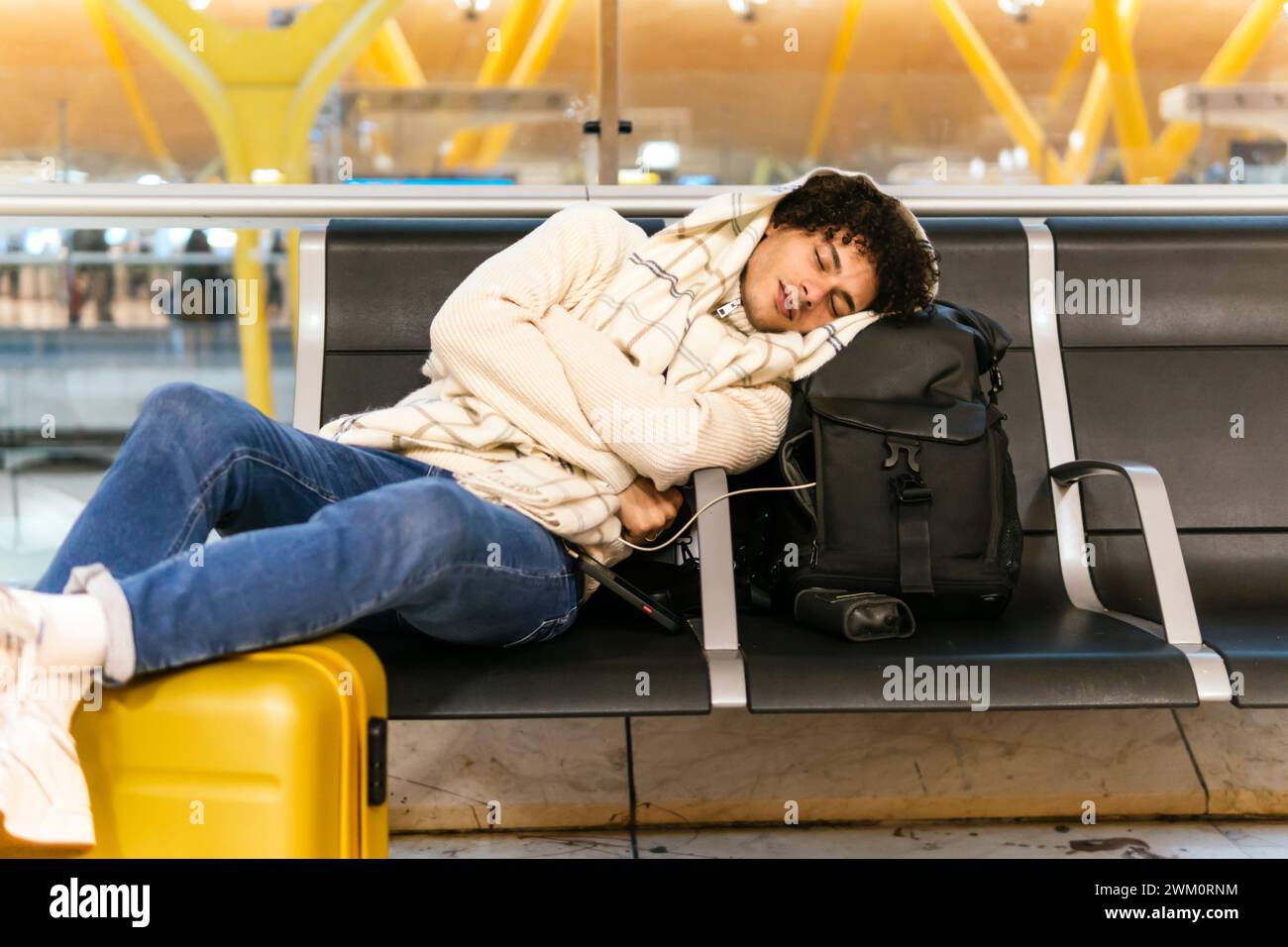 Young man taking nap leaning on backpack at airport lounge Stock Photo ...