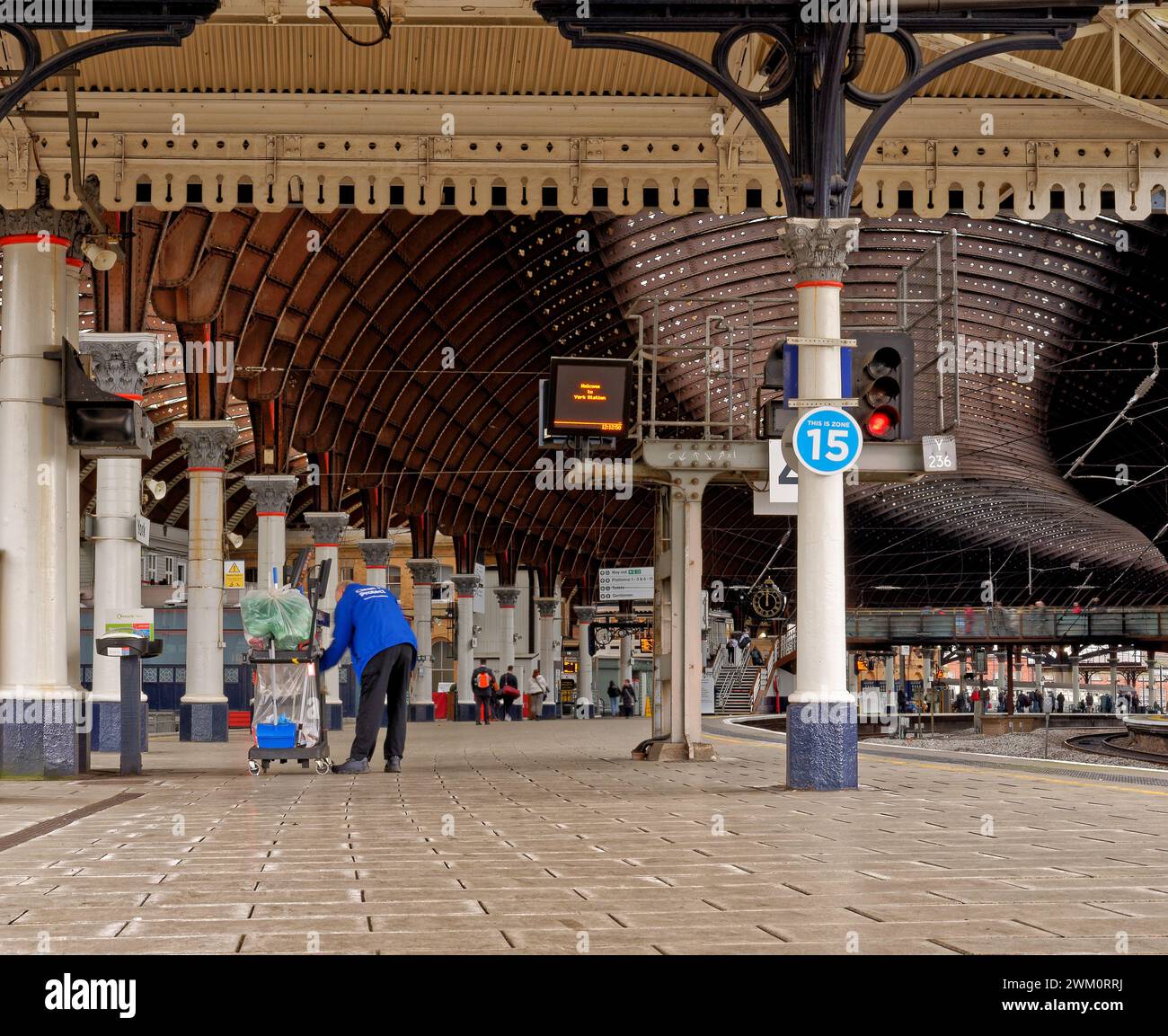 A railway station platform, lined by columns, curves, into a main ...