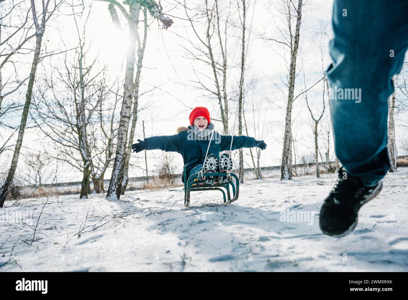Cheerful son enjoying sled ride on snow in winter Stock Photo - Alamy