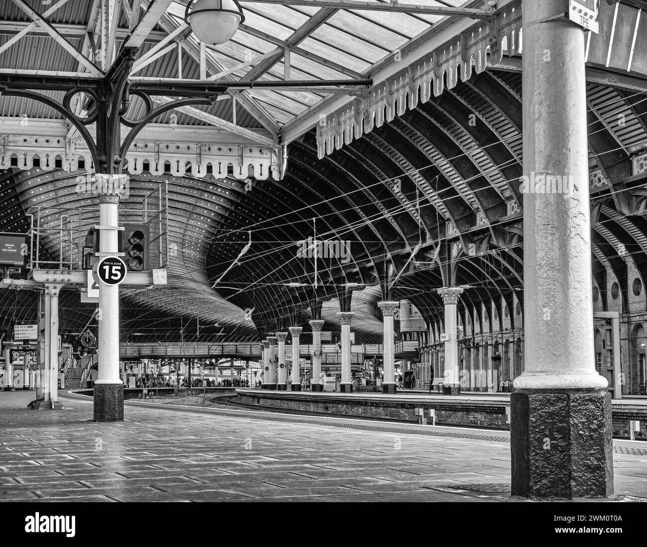 A railway station platform, lined by columns, curves, into a main ...