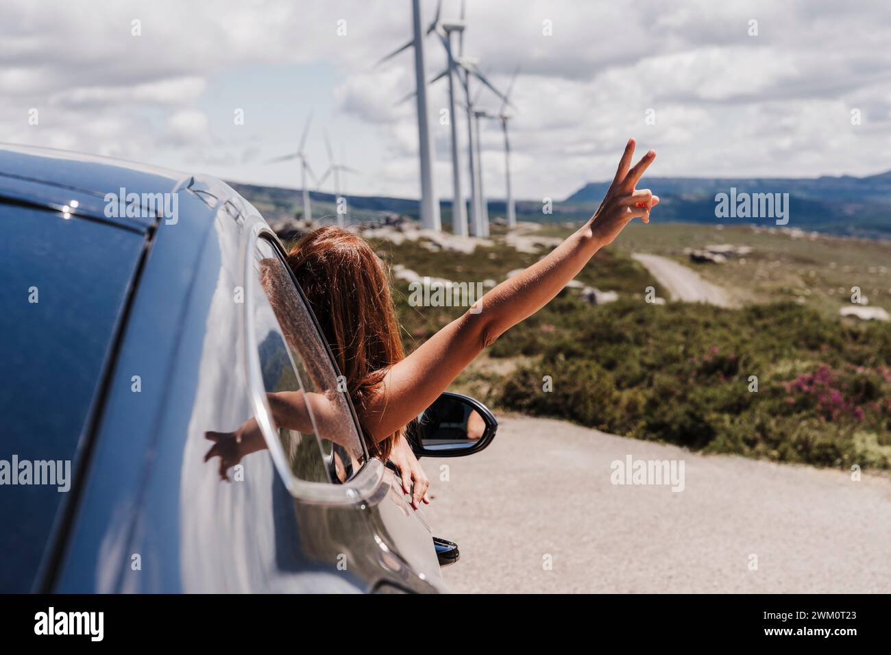 Spain, Madrid, Woman leaning out of car window making peace sign ...