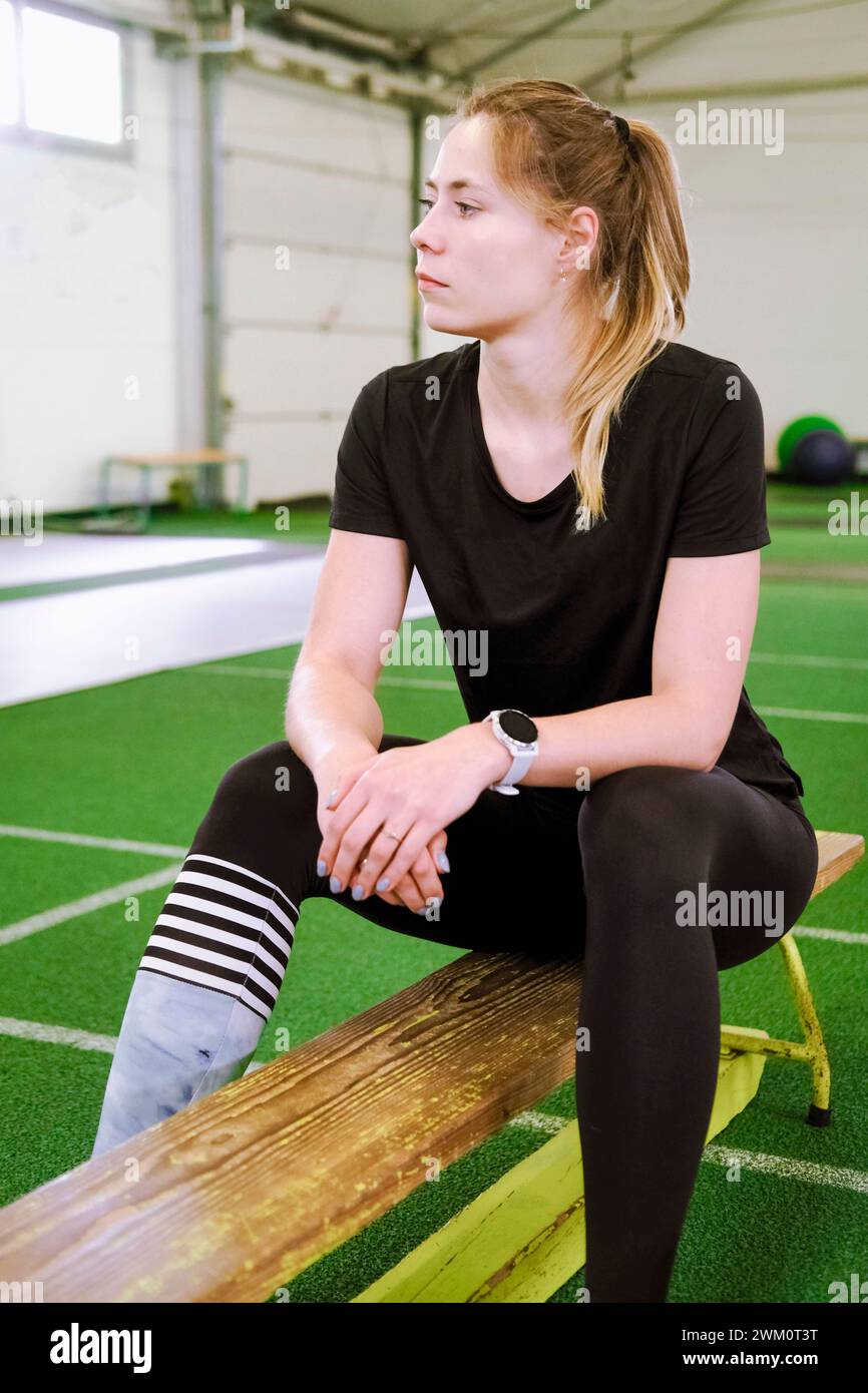 Contemplative woman sitting on bench in gym Stock Photo - Alamy