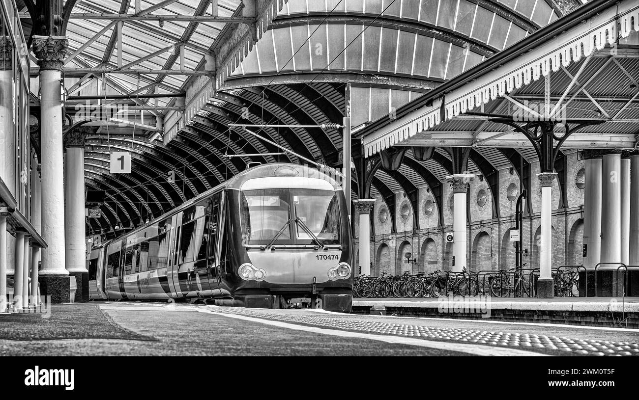 A train sits beside a historic 19th Century railway station platform with a canopy and columns ...