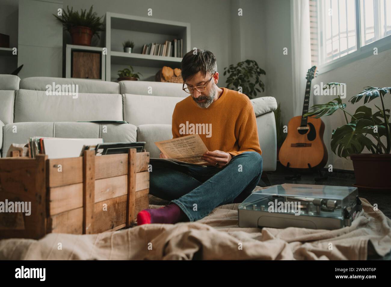 Man reading paper sitting by record player at home Stock Photo - Alamy