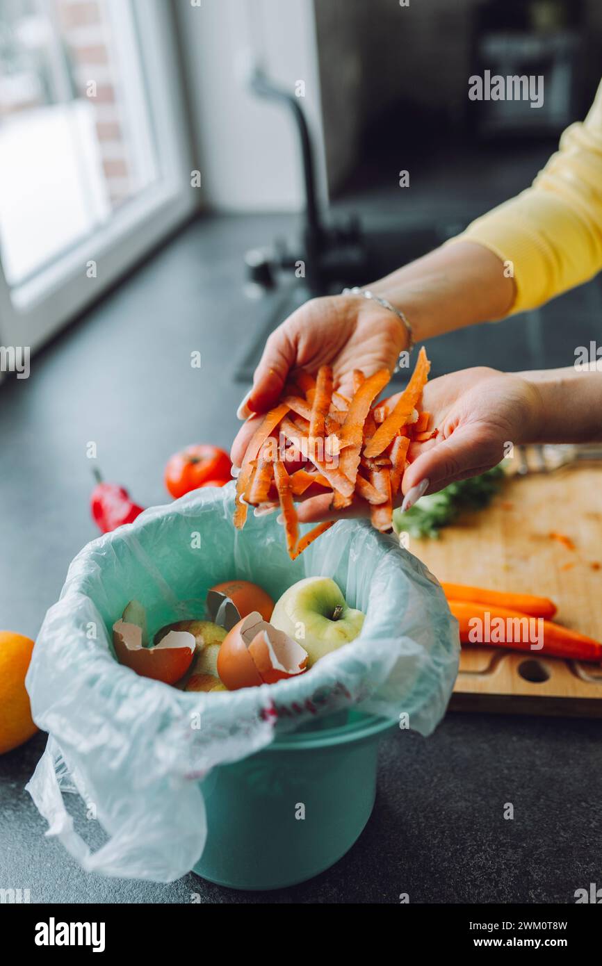 Young woman putting carrot peels in garbage can at home Stock Photo - Alamy