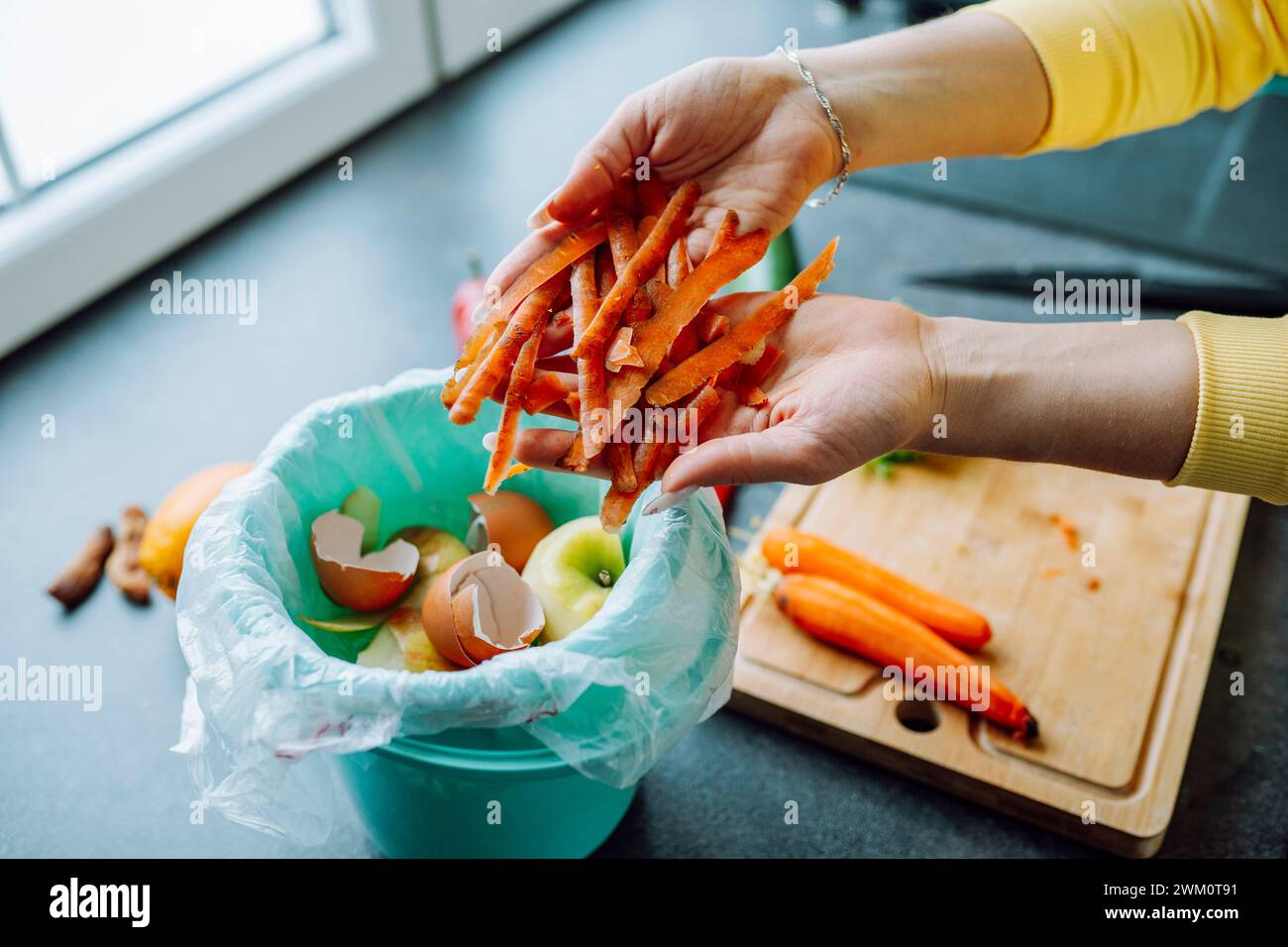 Hands of young woman putting carrot peels in garbage can at home Stock ...