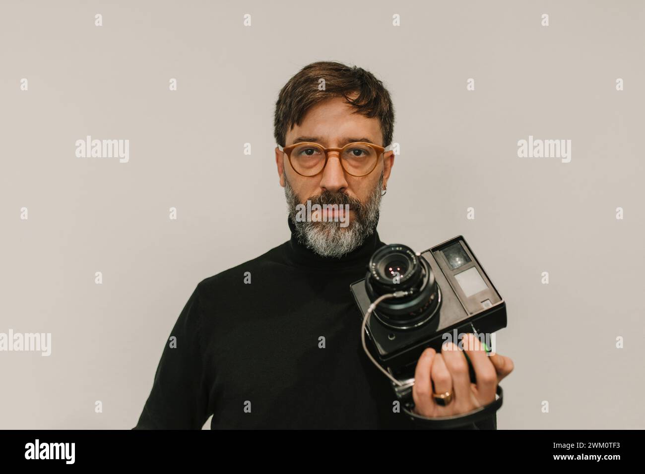 Man holding old instant camera against white background Stock Photo - Alamy