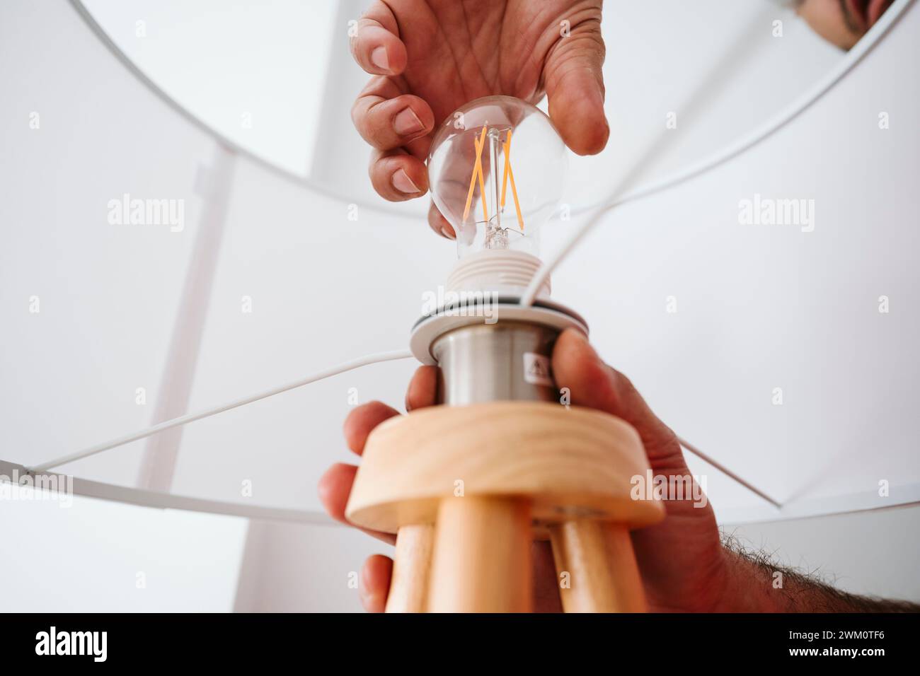 Electrician installing light bulb in electric lamp at home Stock Photo ...