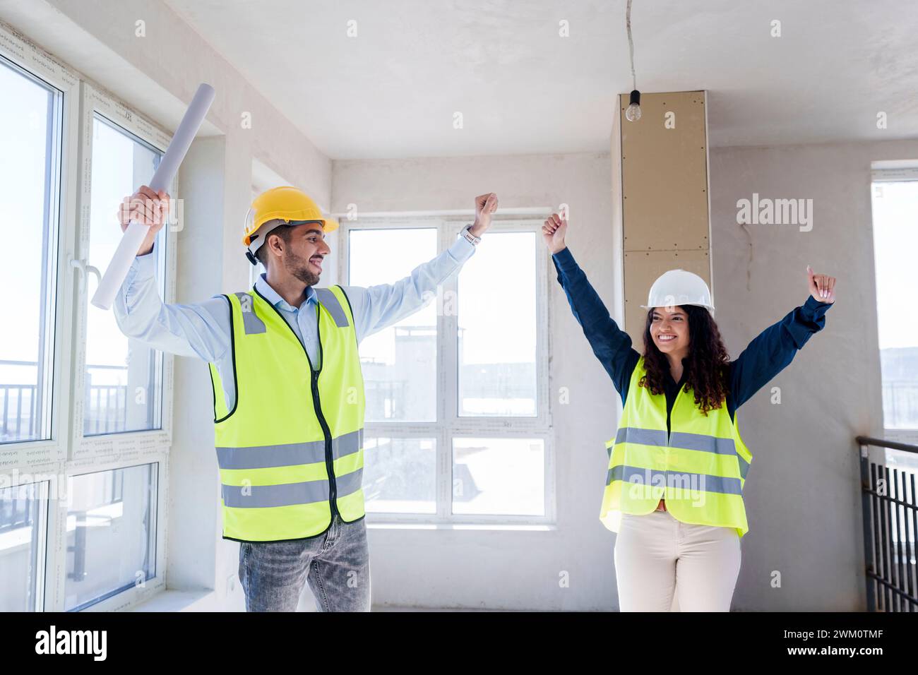 Happy construction engineers cheering at site Stock Photo - Alamy