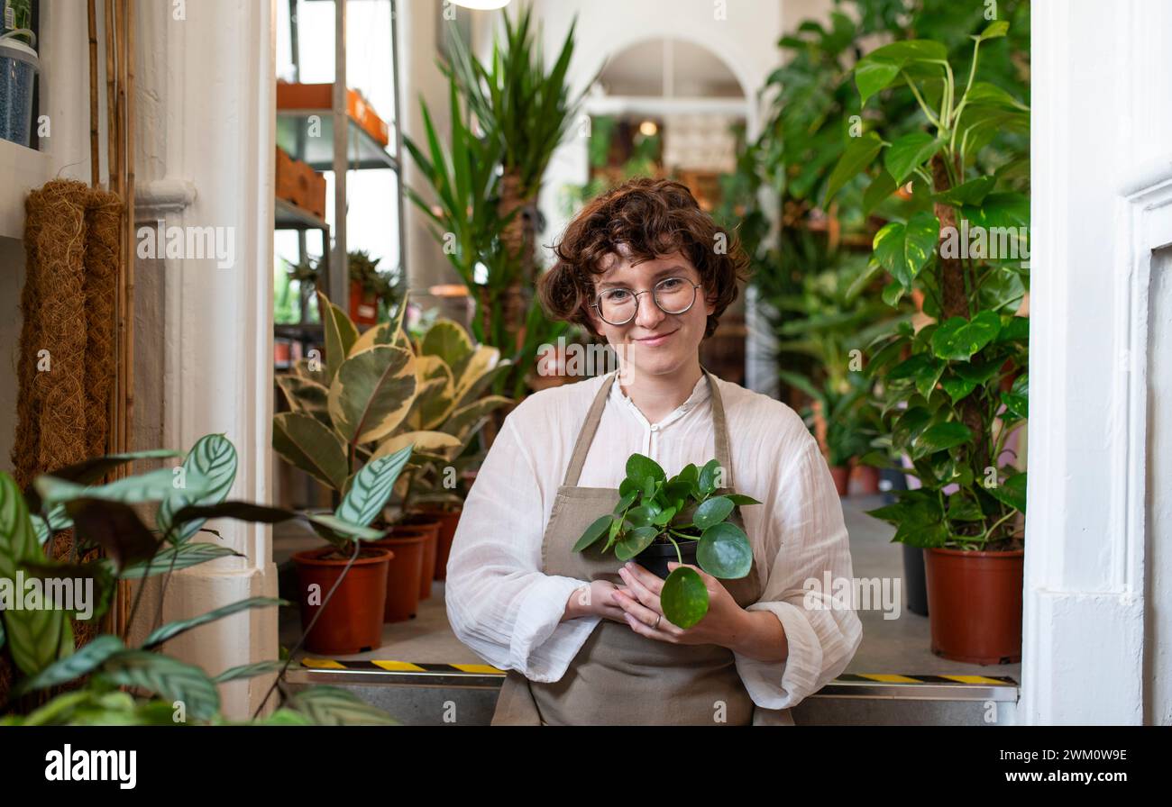 Smiling botanist holding potted plant at nursery Stock Photo - Alamy