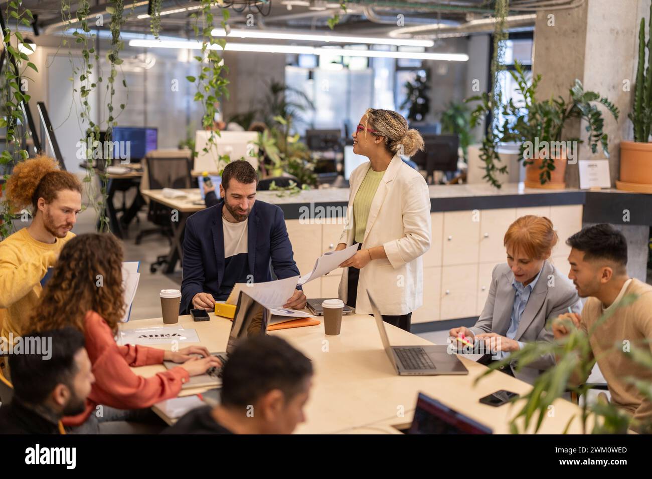 Young businesswoman explaining strategy to diverse colleagues at ...