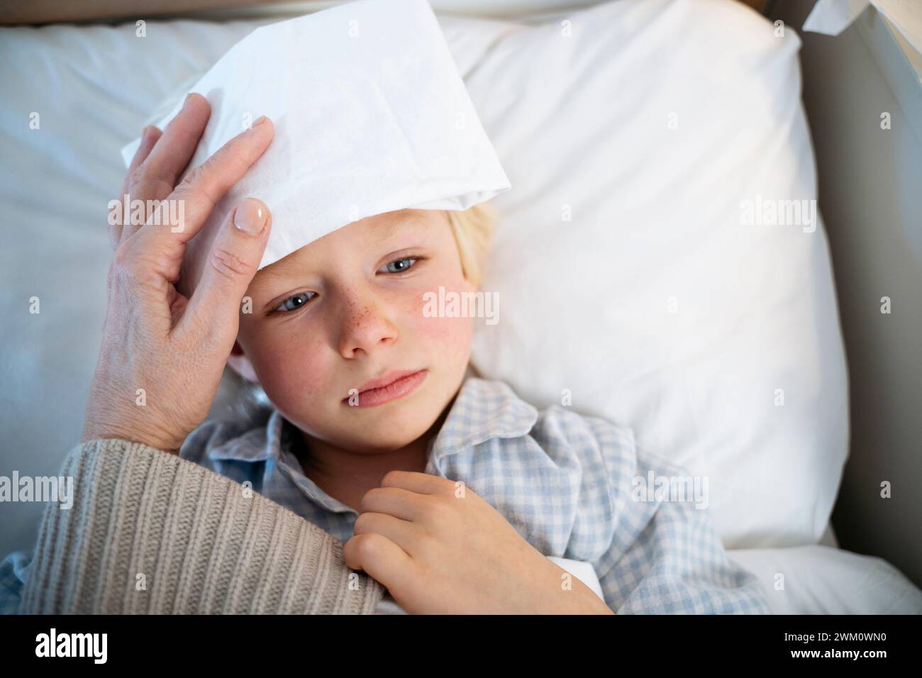 Thoughtful sick boy with white compress on forehead at home Stock Photo ...