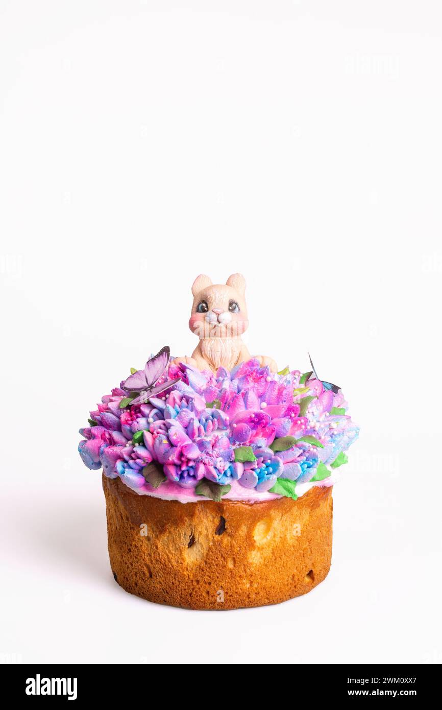 The image shows a small round cake with pink and purple flowers and a ...