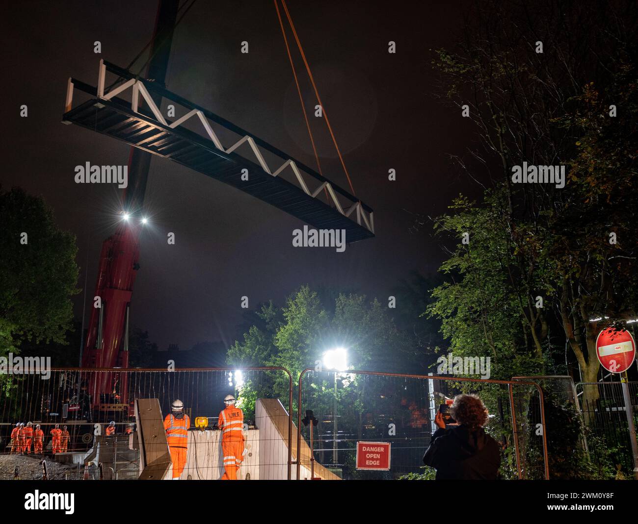 A completed pedestrian bridge is craned from height into place at night in Strathbungo, Glasgow ...