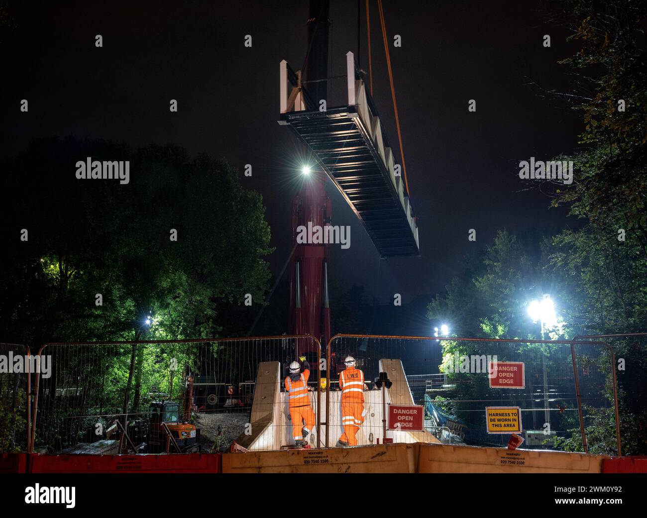 A completed pedestrian bridge is craned from height into place at night in Strathbungo, Glasgow ...