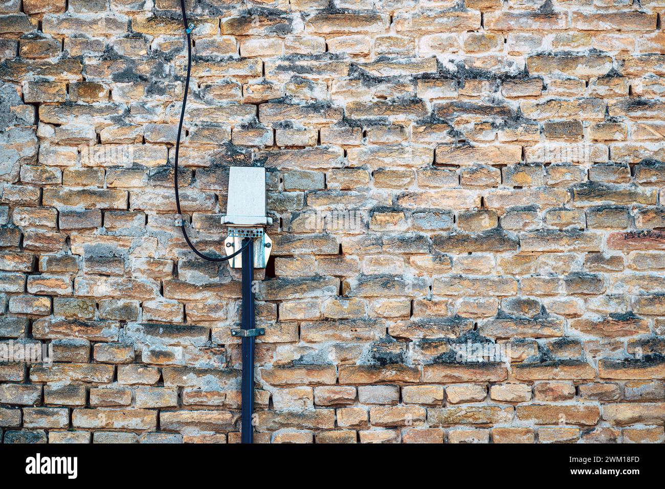 Electrical cable and wires installation on old brick wall as background ...
