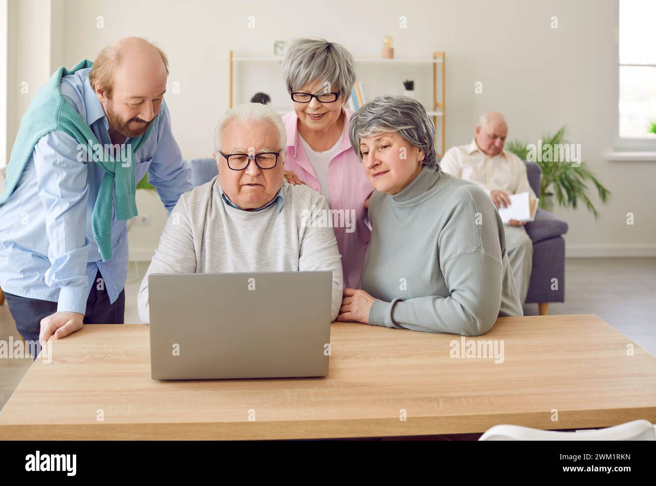 Group of several elderly people using laptop computer in living room at ...