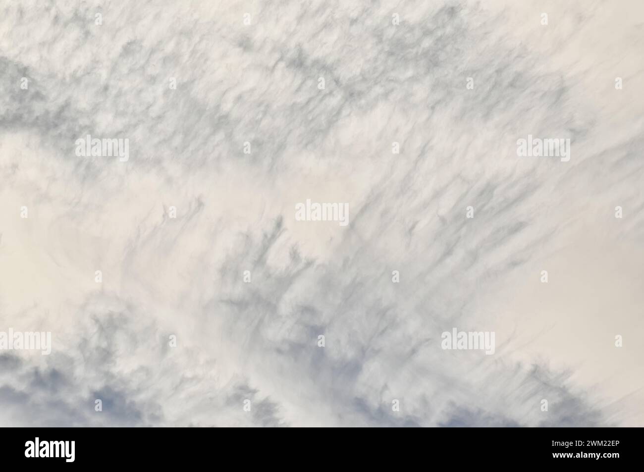 Wispy clouds spread across a soft blue sky, creating a serene ...