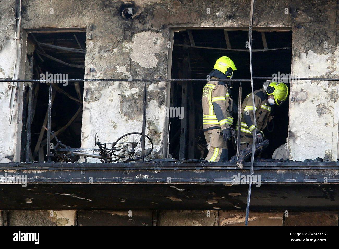 Firefighters remove a charred body inside a burned block building in ...