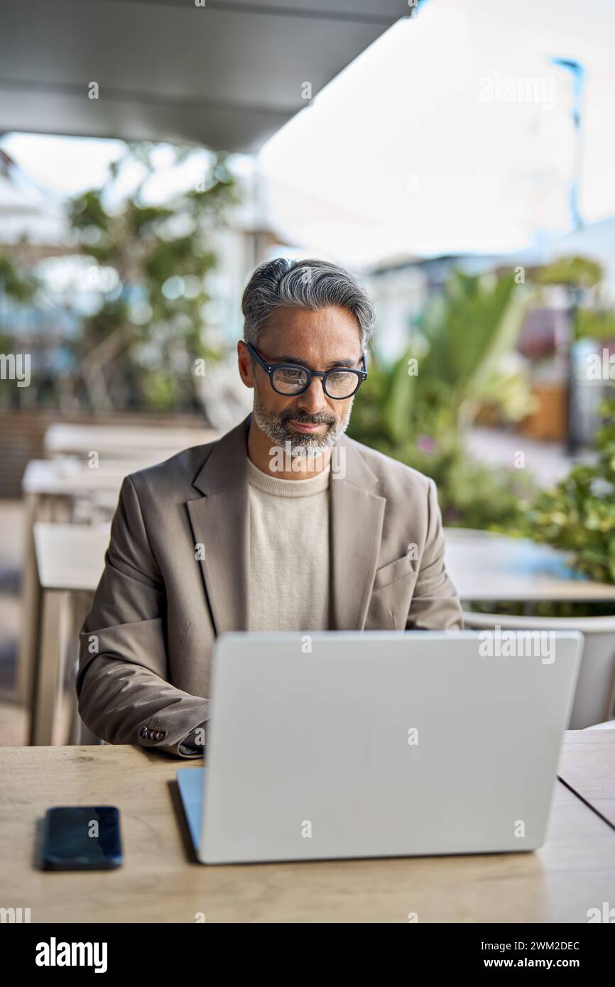 Middle aged business man executive sitting at outdoor table using ...