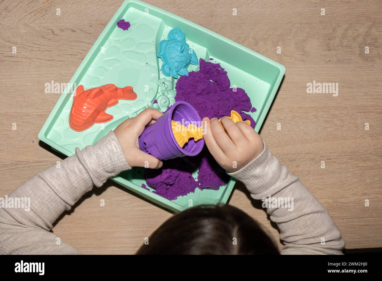 A child is using their fingers to create art with violet and magenta ...