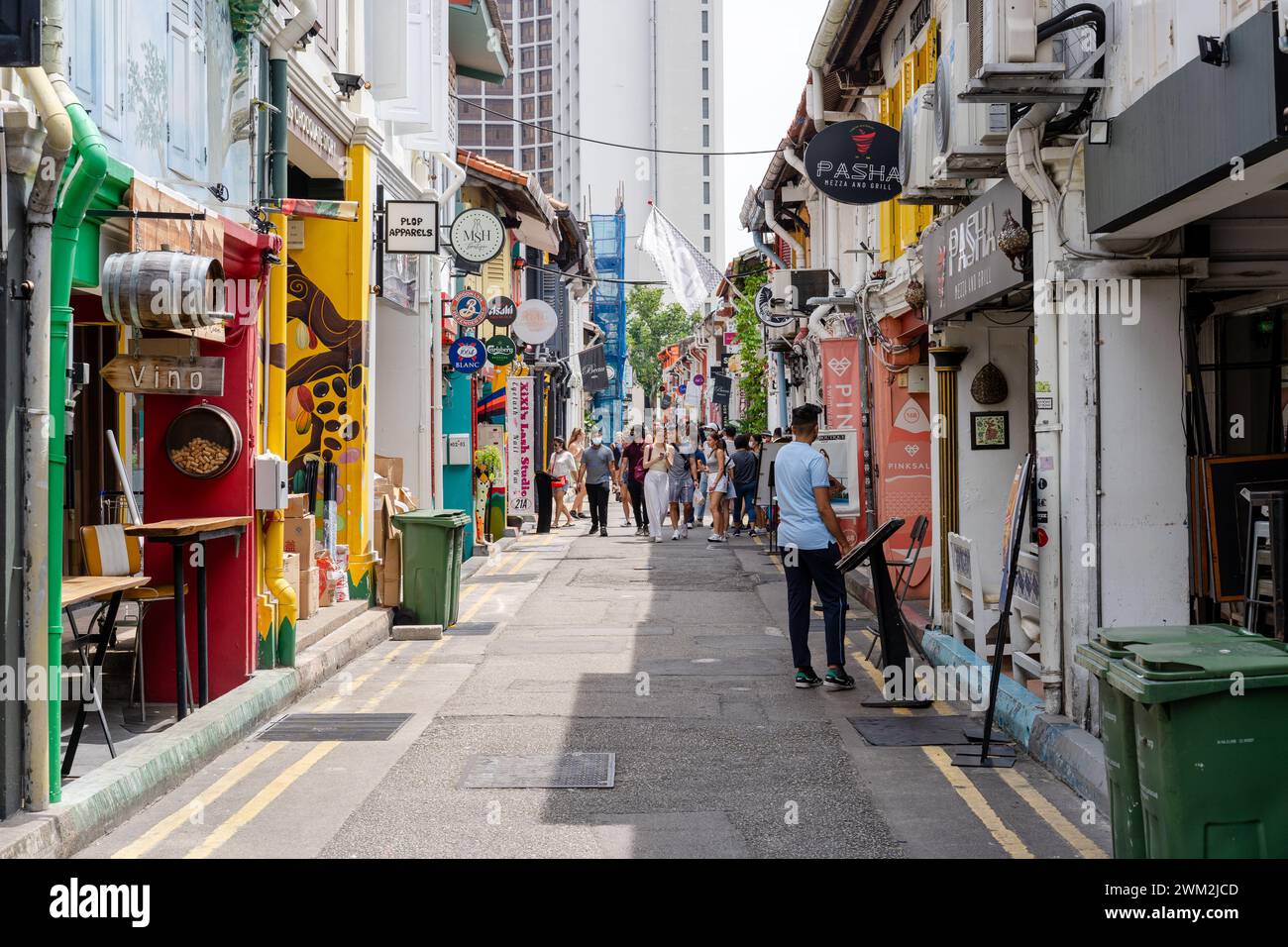 Crowd strolling through urban alley lined with shops Stock Photo - Alamy