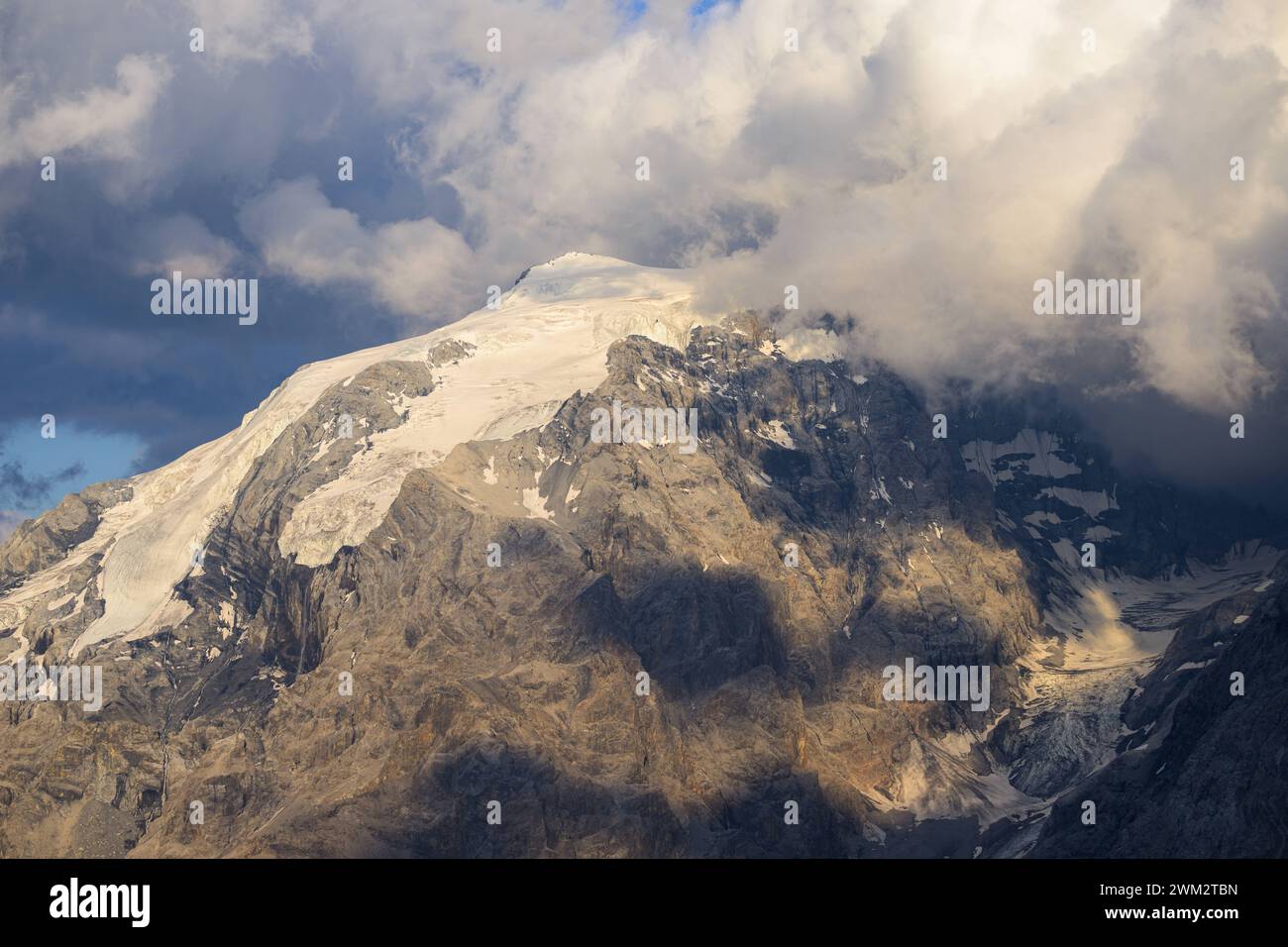 The Ortler Alps near Stelvo Pass at sunset in summer, clouds around the ...