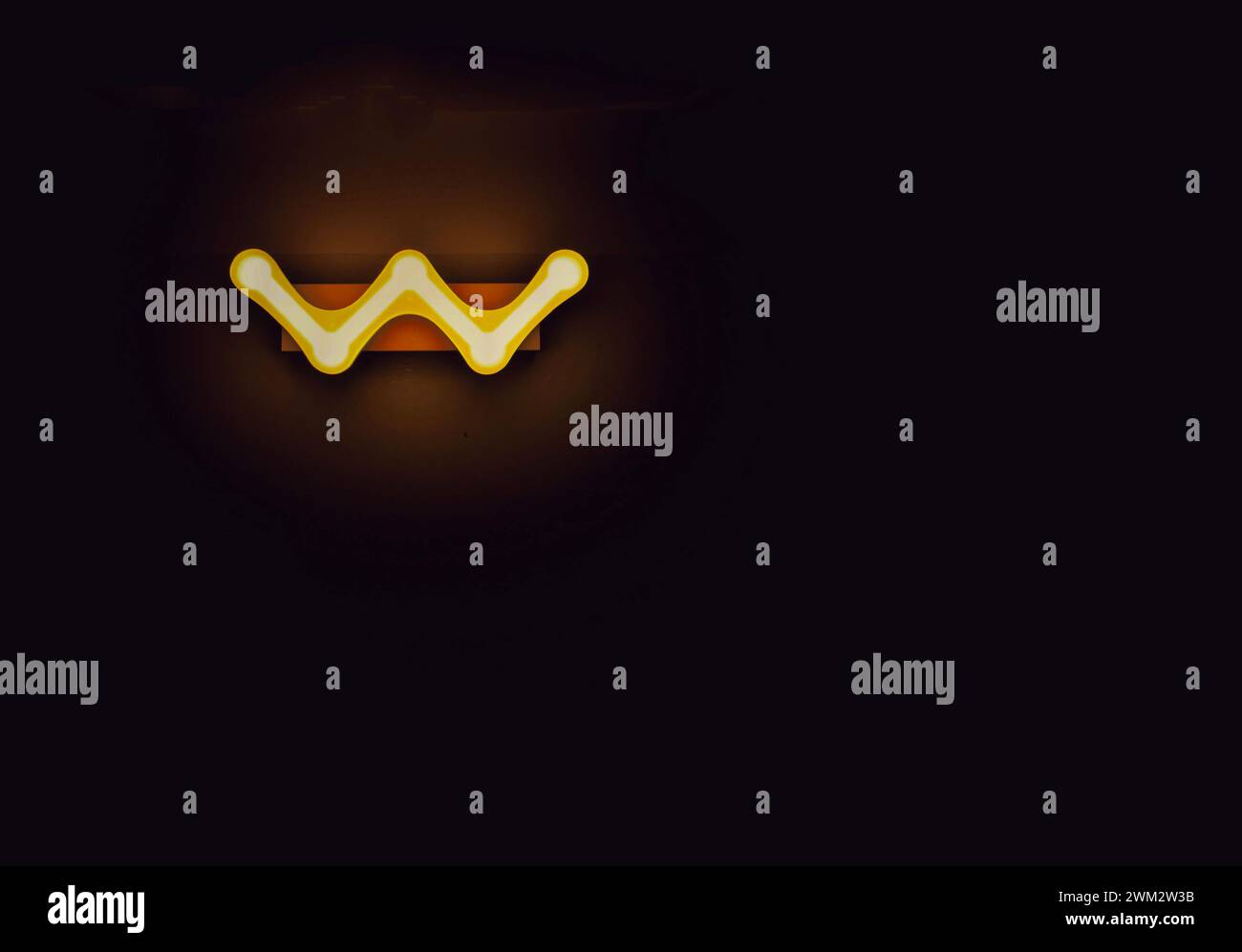 An Illuminated yellow logo design W against dark backdrop Stock Photo ...