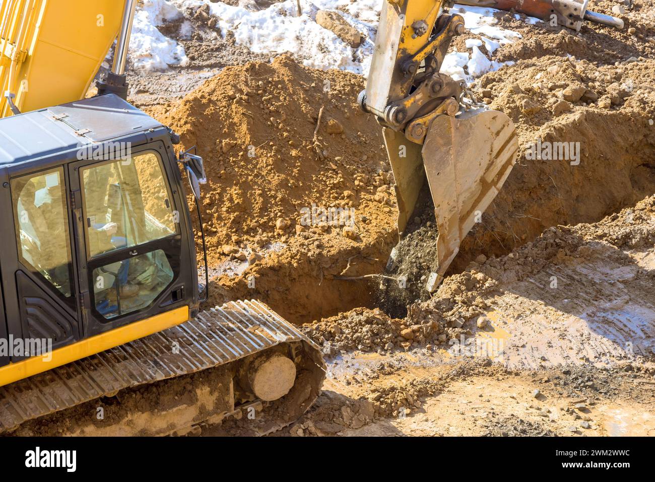 Trench is dug by an excavator as part of earthmoving operations at construction site to prepare ...