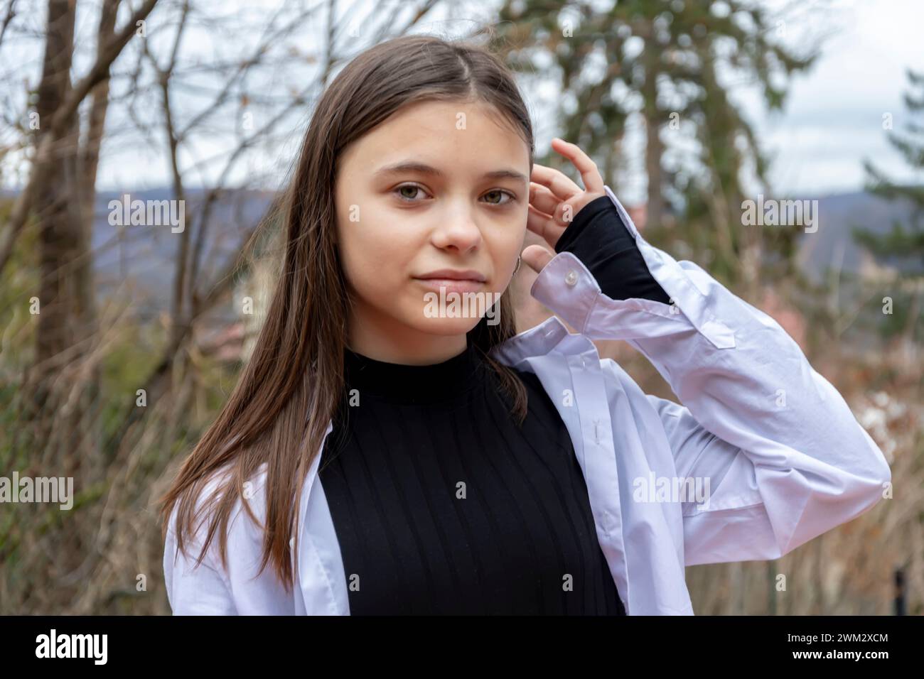 A teenage girl of 12 years old fixes her long hair in the background of ...