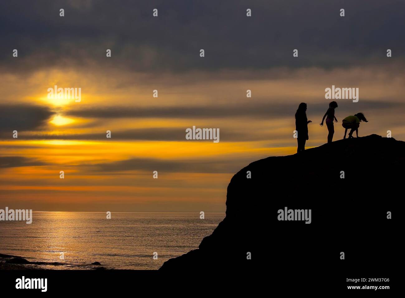 Silhouette of three teen girls on seaside cliff at sunset Stock Photo ...