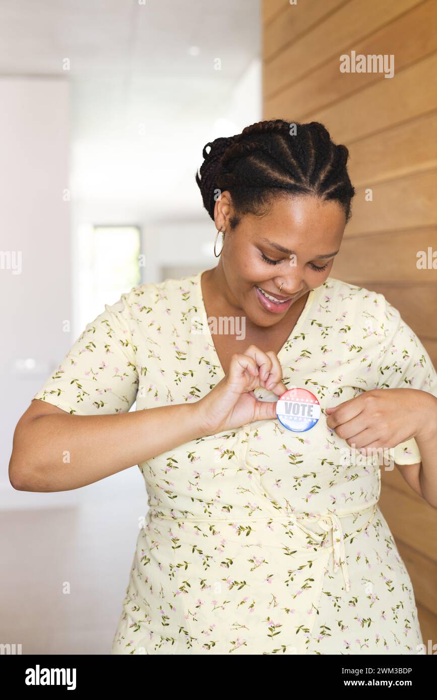Young biracial woman pins a 'vote' badge on her top Stock Photo - Alamy