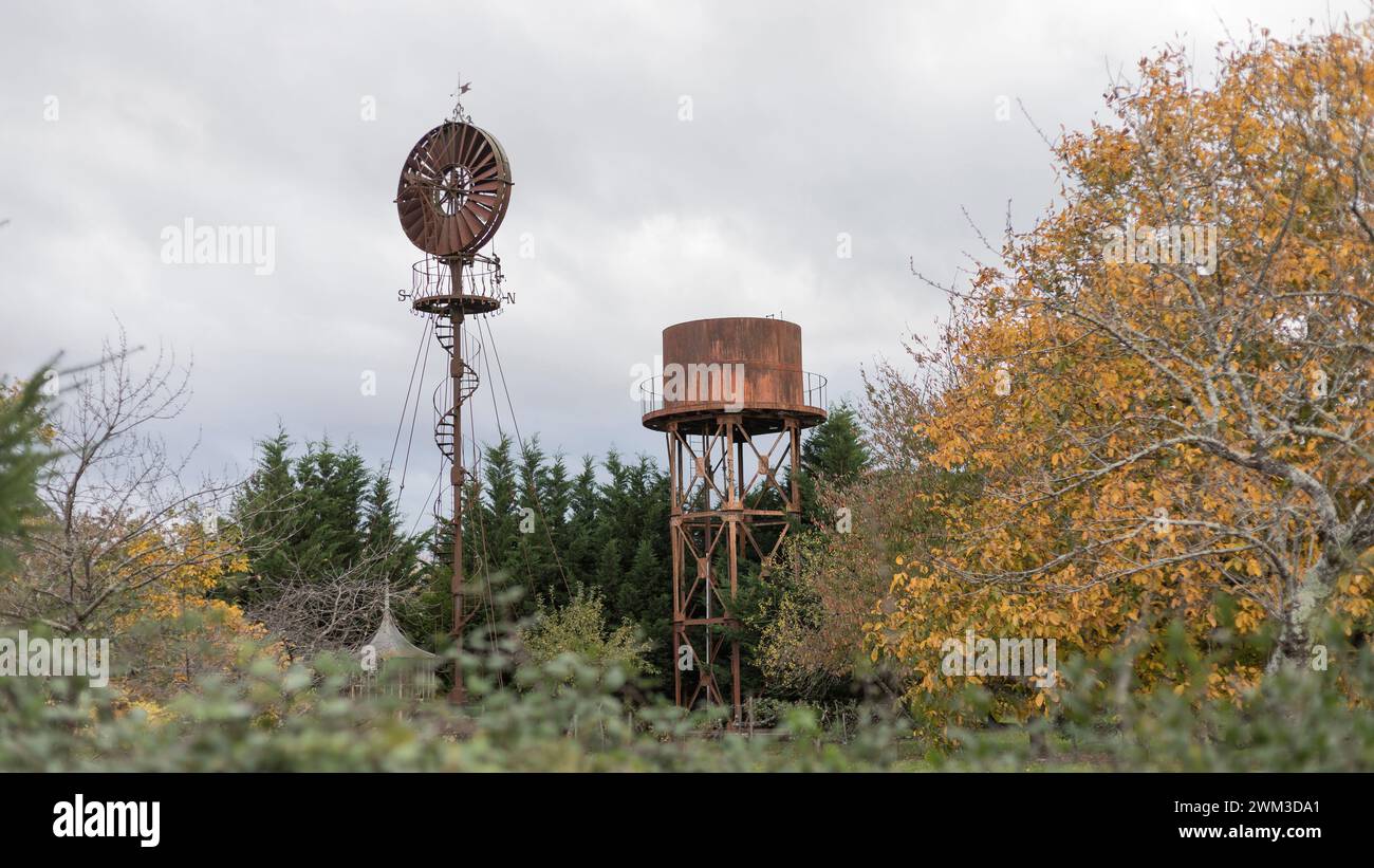 Rust coloured metal wind structure and water tower in a garden Stock ...